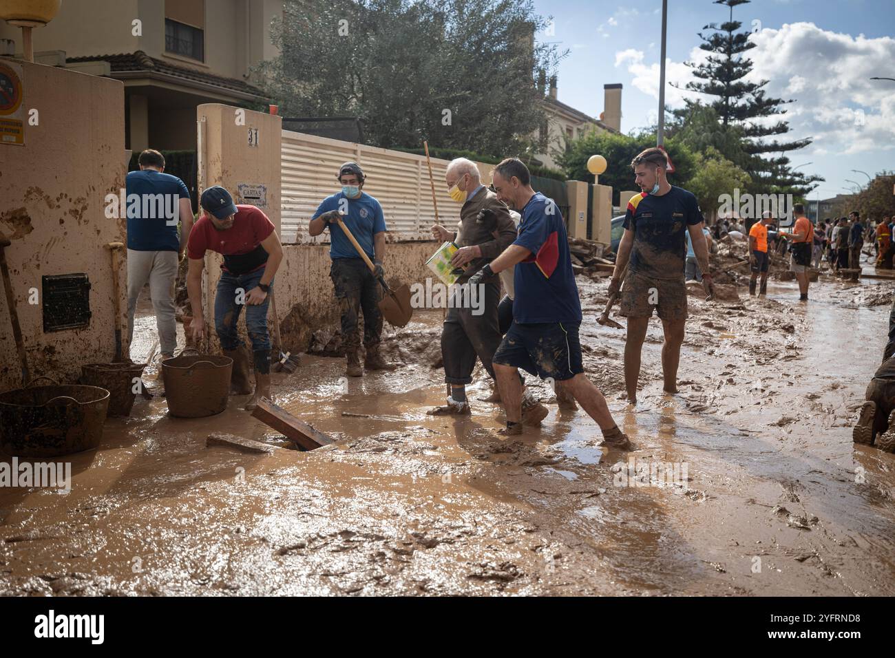 People helps out an elderly man to cross the street full of mud while ...