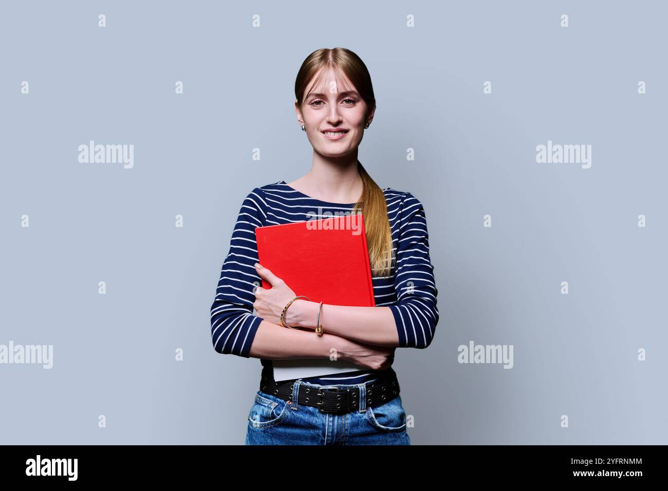 Portrait of teenager student girl holding notebook on gray studio ...