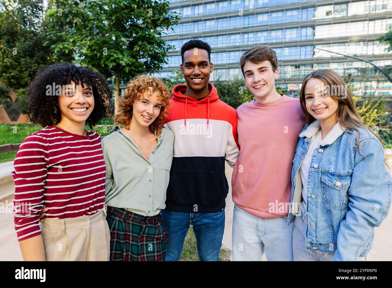 Portrait group of five young teenage friends smiling at camera standing ...