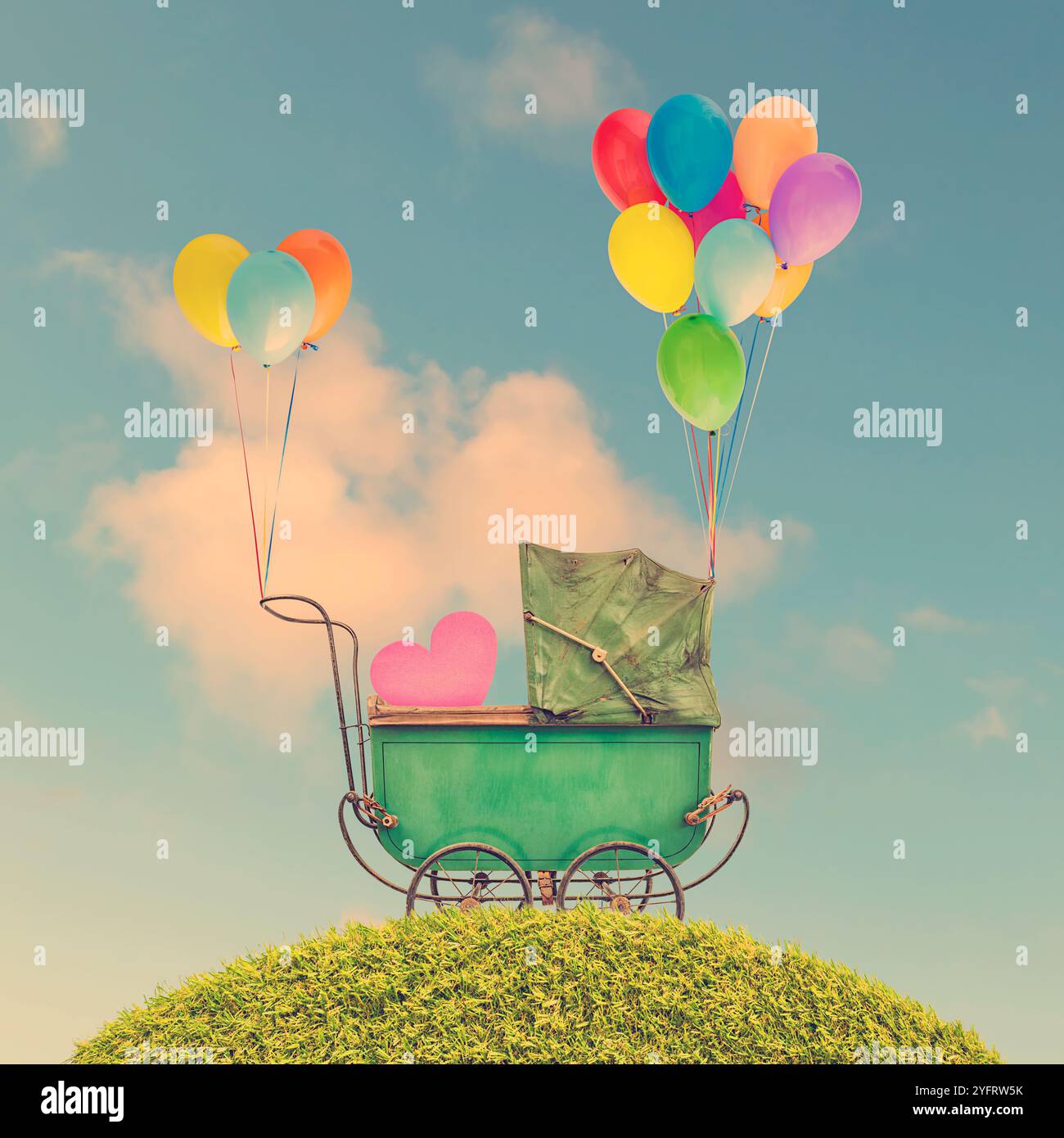 Vintage baby stroller with heart and balloons on a field of grass with ...