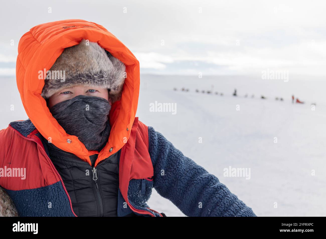 Adult caucasian male musher dressed in full arctic gear on snowy tundra ...