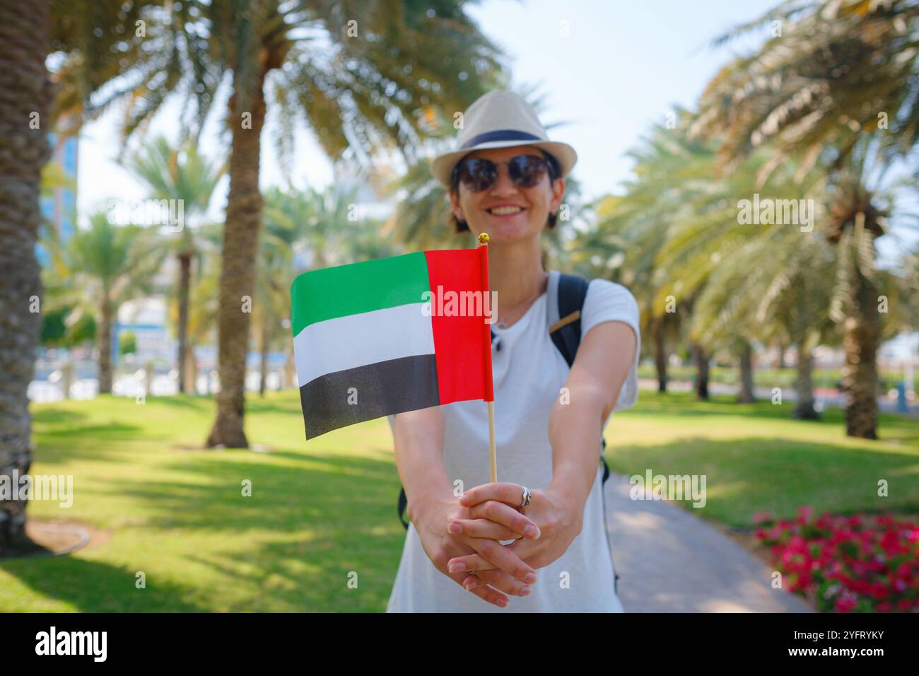 woman holding tiny flag of UAE against Abu Dhabi skyline, Promenade in ...