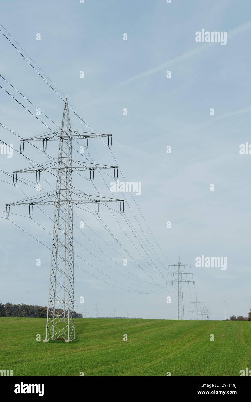 High voltage power lines leading through a green field. Transmission of ...