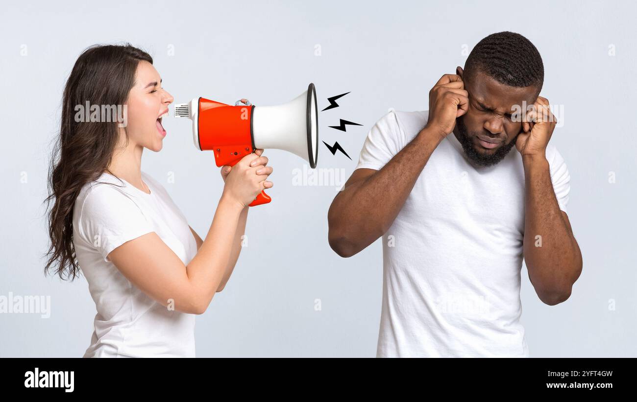Angry woman shouting at her boyfriend with loudspeaker over light ...