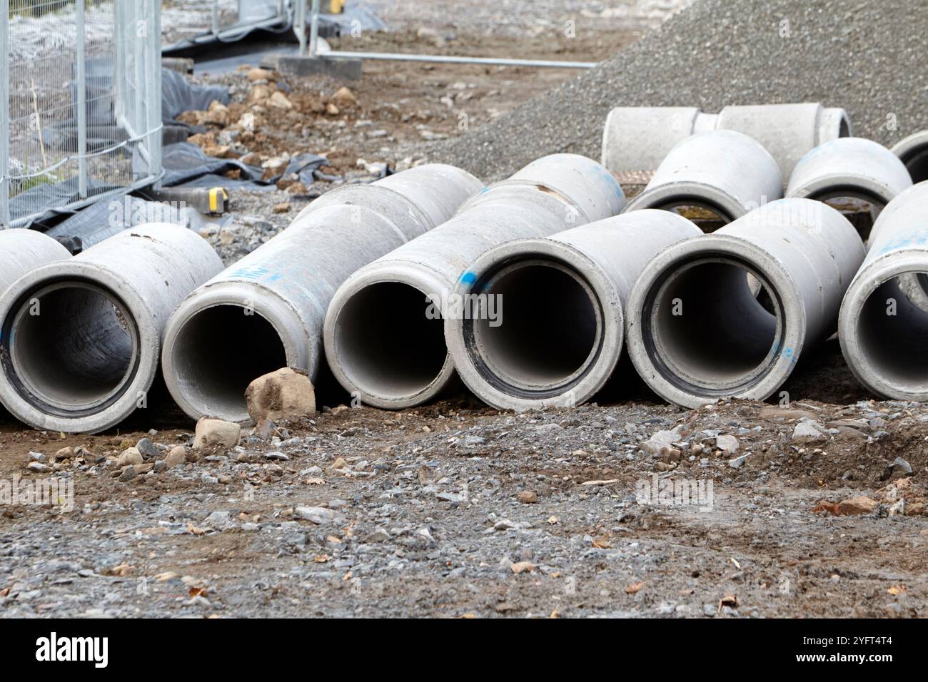 concrete drainage pipes piled up for installation on a commercial site ...