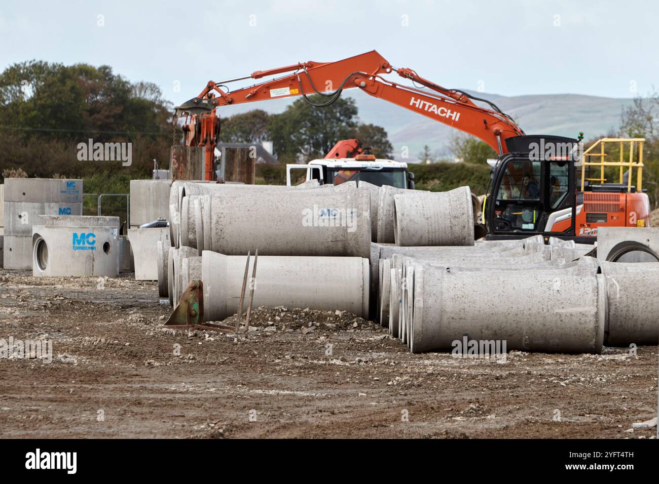 concrete drainage pipes piled up for installation on a commercial site ...