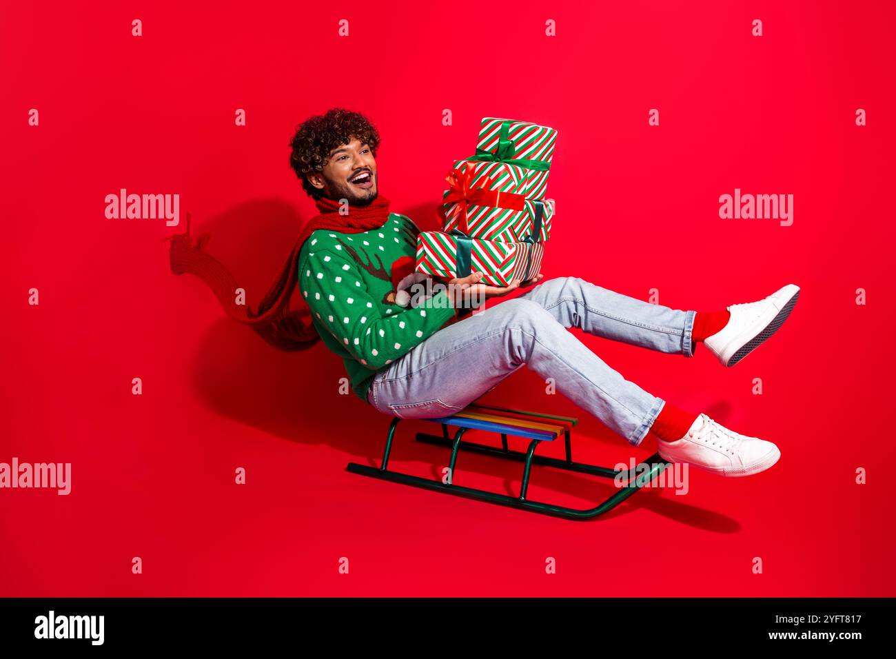 Full body photo of attractive young man ride sledge hold gifts dressed ...