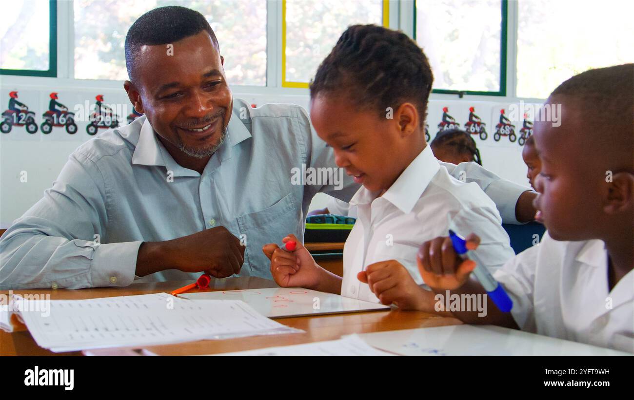 A teacher engages with two students working on their assignments Stock ...