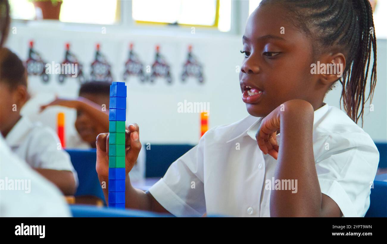 A girl is focused on building a tall tower with colorful blocks Stock ...