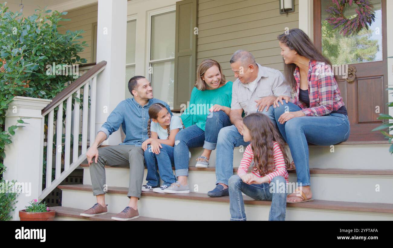 Multi Generation Family Sit On Steps Leading Up To House Porch Stock