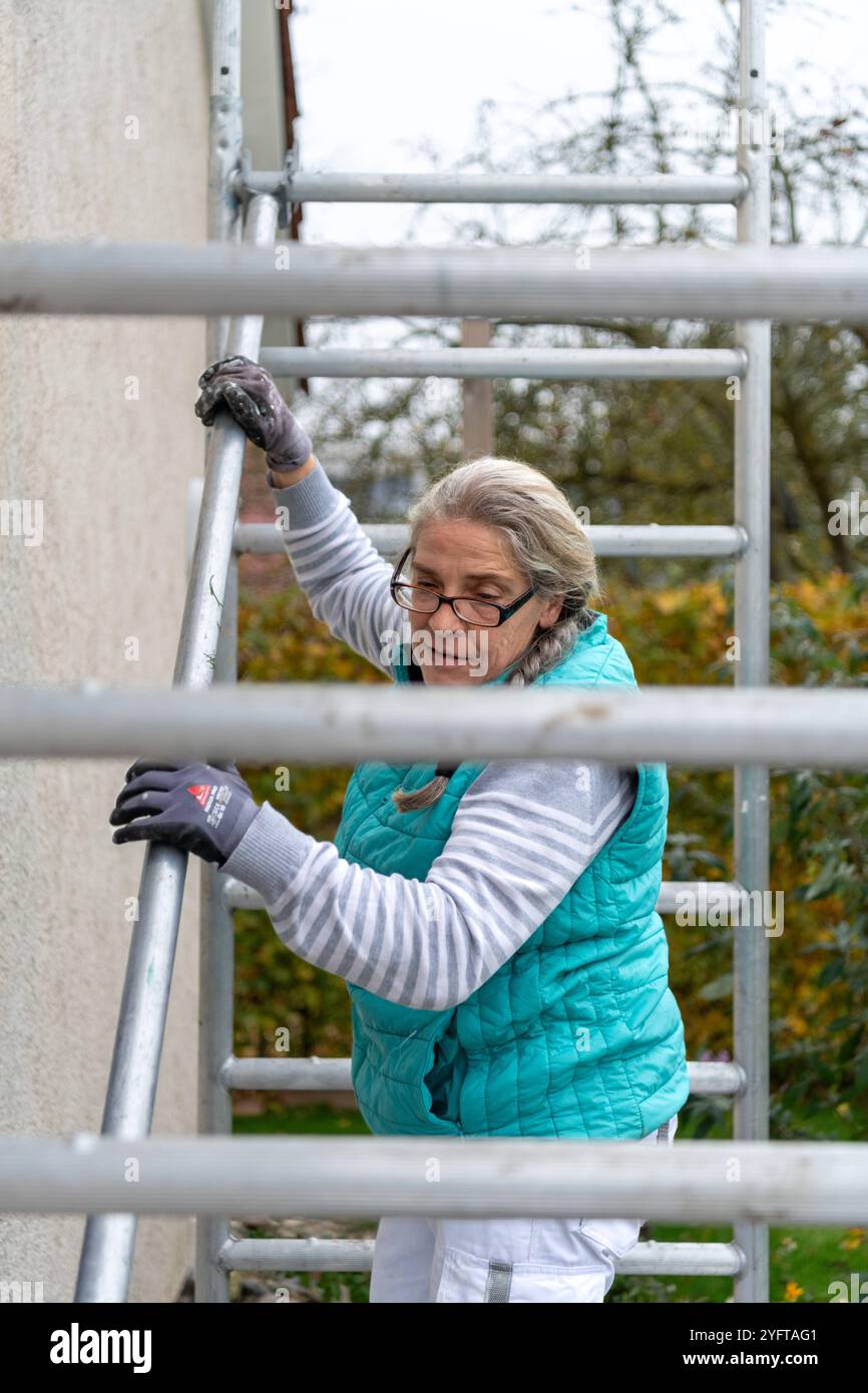 Gerüstbauerin, Malerin baut ein mobiles Gerüst am Einfamilienhaus auf ...
