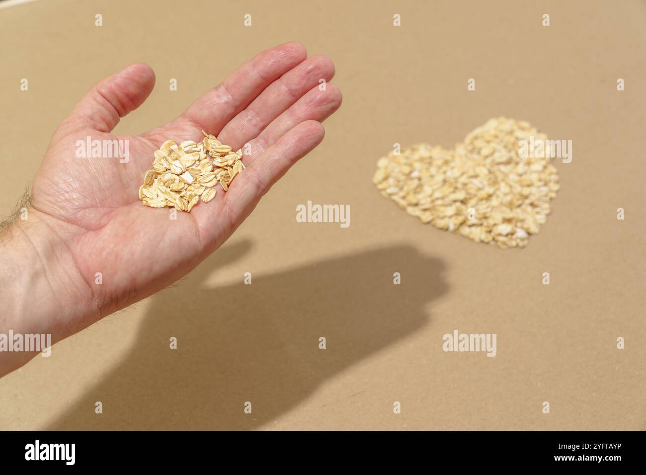 Male caucasian hand holding oats. Groats in shape of heart. Top view ...