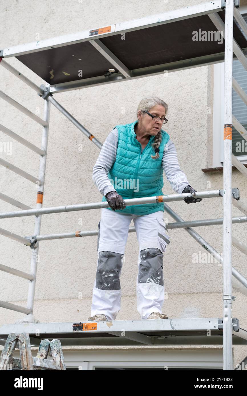 Gerüstbauerin, Malerin baut ein mobiles Gerüst am Einfamilienhaus auf ...