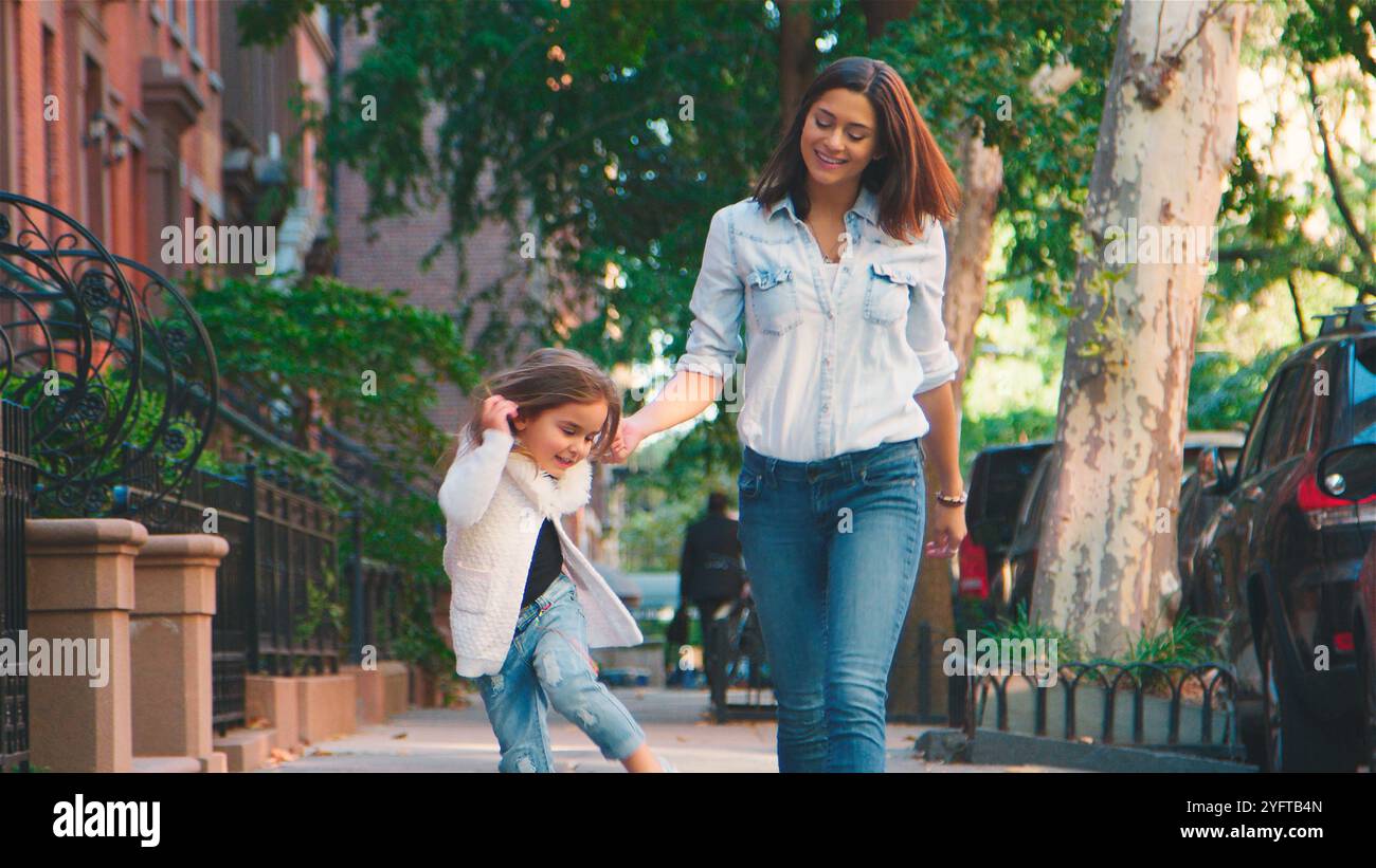 Family Shot With Mother And Daughter Walking Holding Hands Along Urban ...