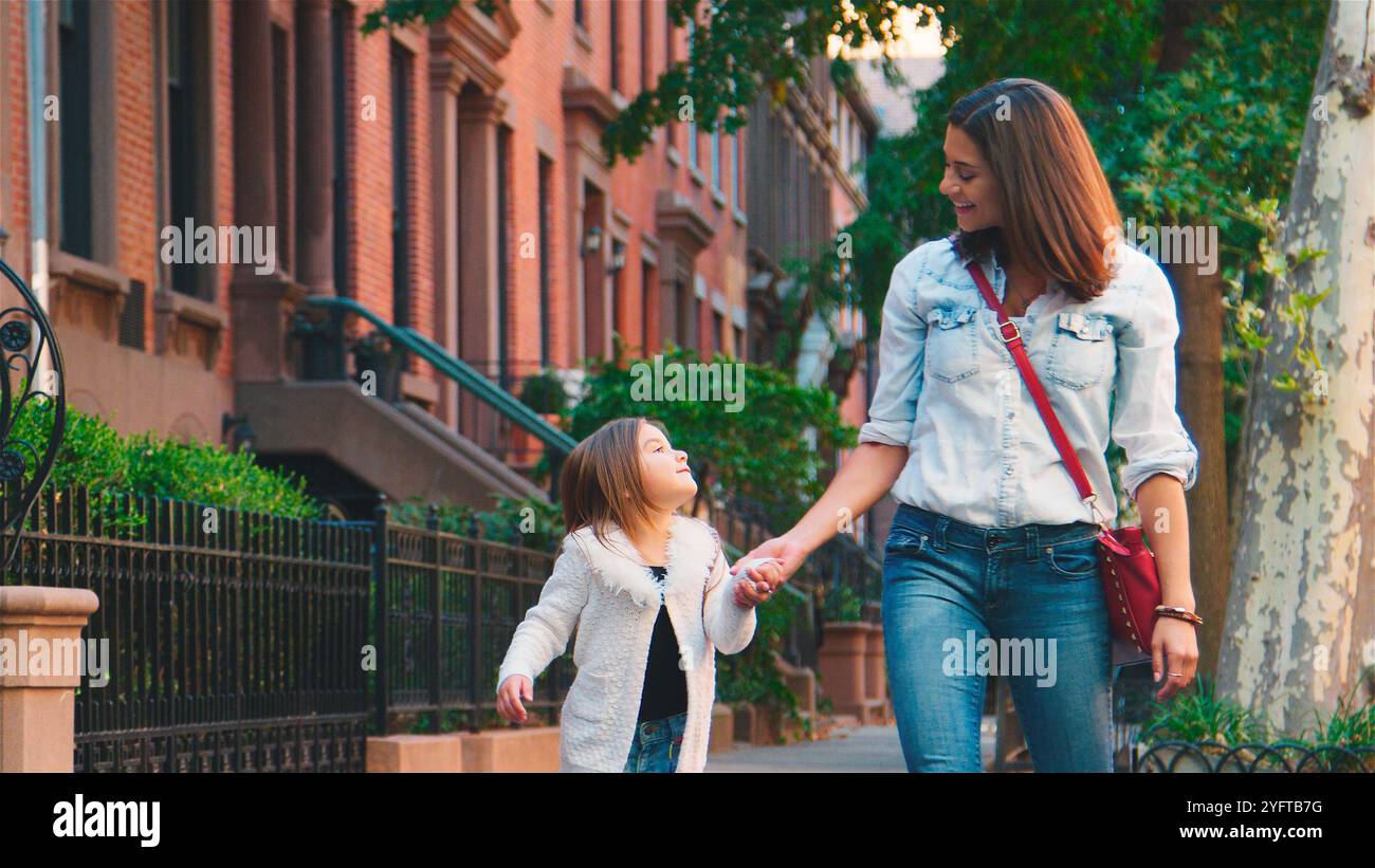Family Shot With Mother And Daughter Walking Holding Hands Along Urban ...