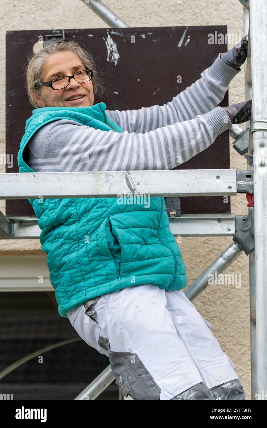 Gerüstbauerin, Malerin baut ein mobiles Gerüst am Einfamilienhaus auf, model released für ...
