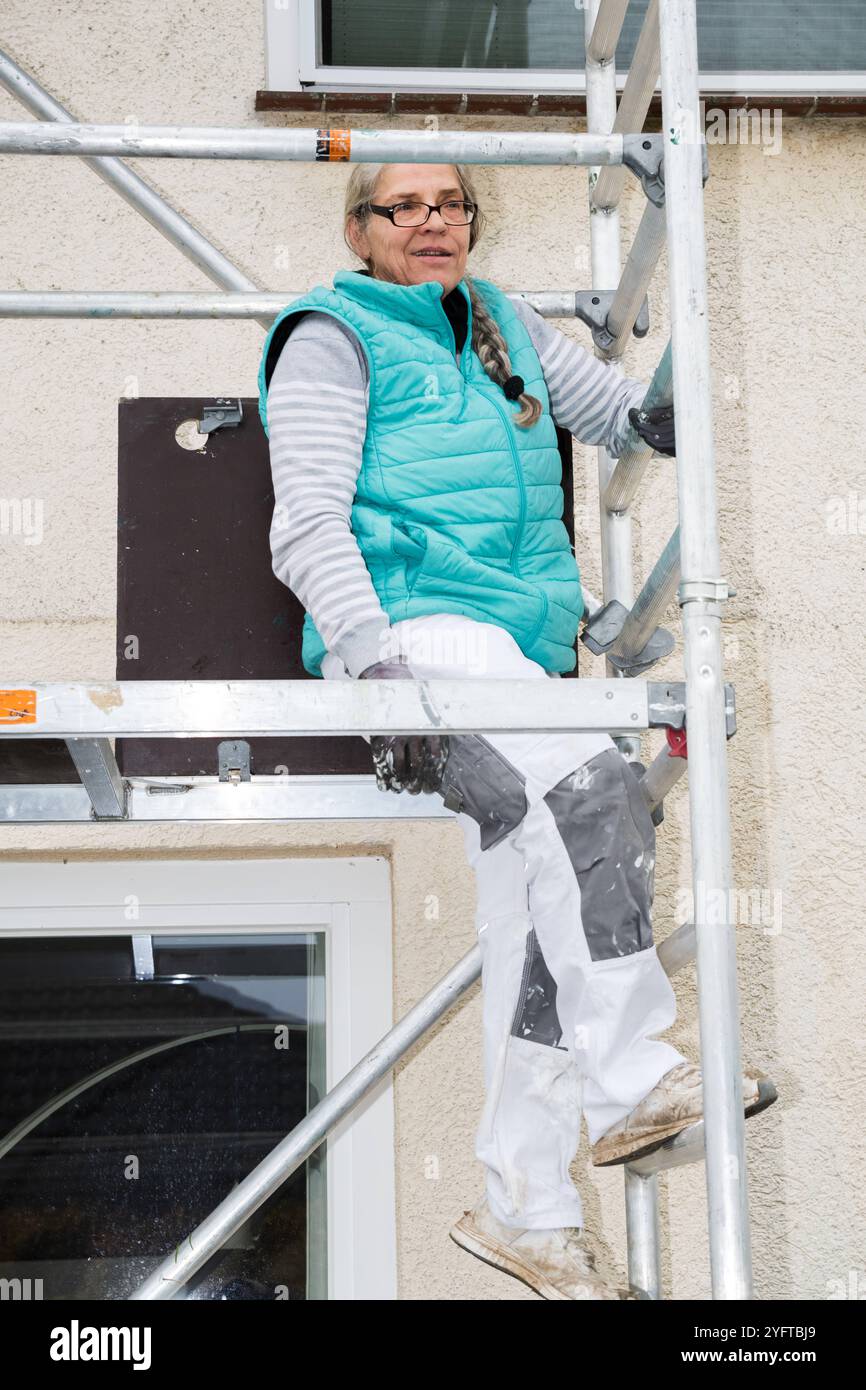 Gerüstbauerin, Malerin baut ein mobiles Gerüst am Einfamilienhaus auf, model released für ...
