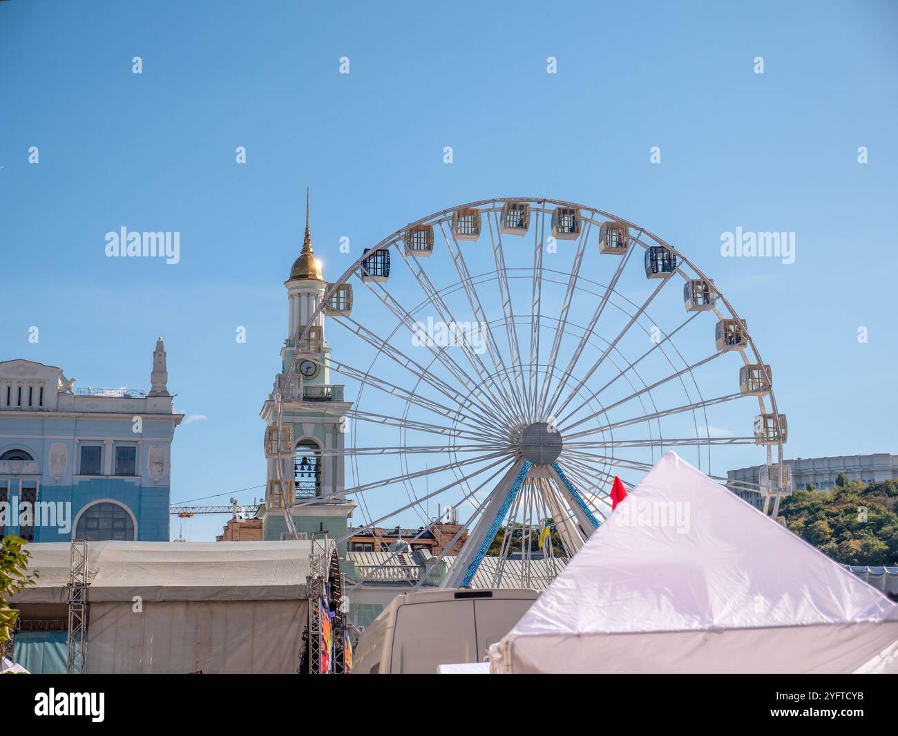 Modern observation wheel and ancient church bell tower with bright blue ...