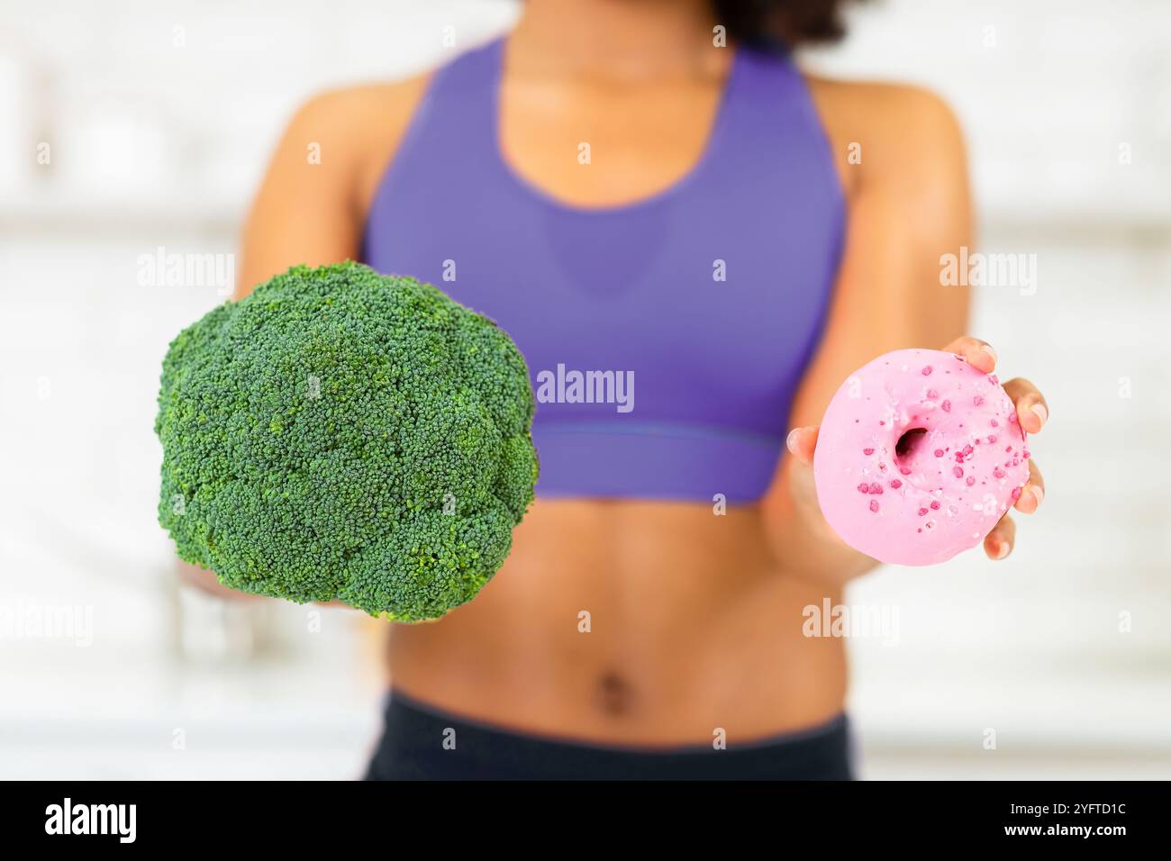 Fit Afro Girl Holding Broccoli And Doughnut Stock Photo - Alamy