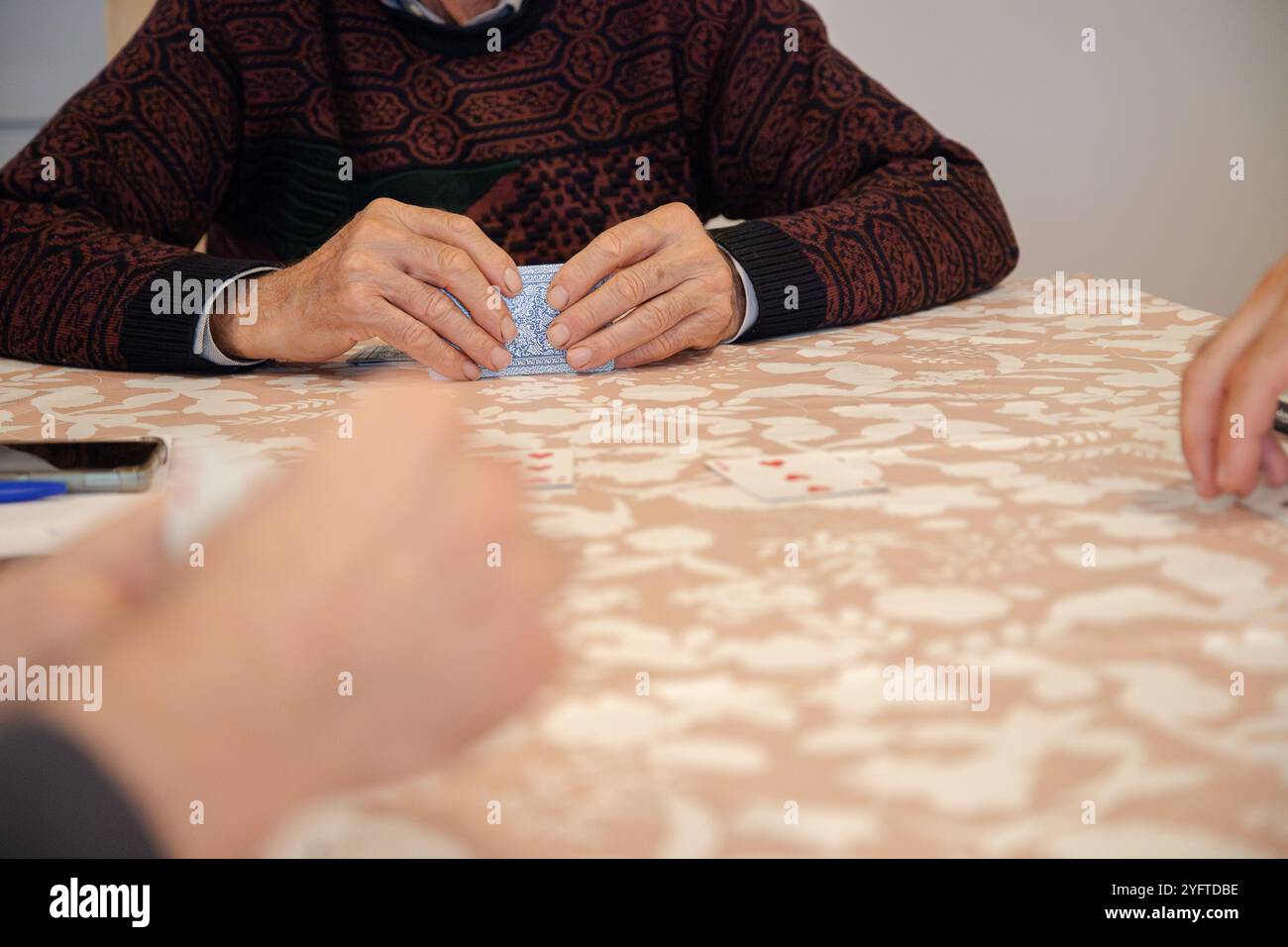 A group of people gather around a table playing cards, a casual game ...