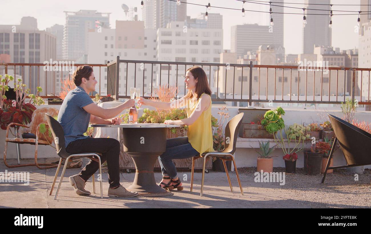 Couple Drinking Wine And Making Toast On Rooftop Terrace With City ...