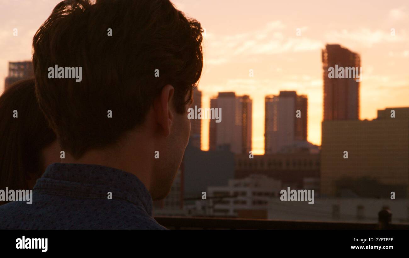 Rear View Of Couple On Rooftop Terrace With City Skyline In Background ...