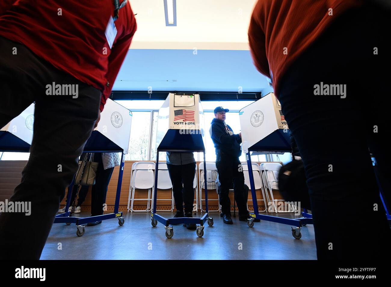 People stand behind privacy voting booths as they fill out their ...