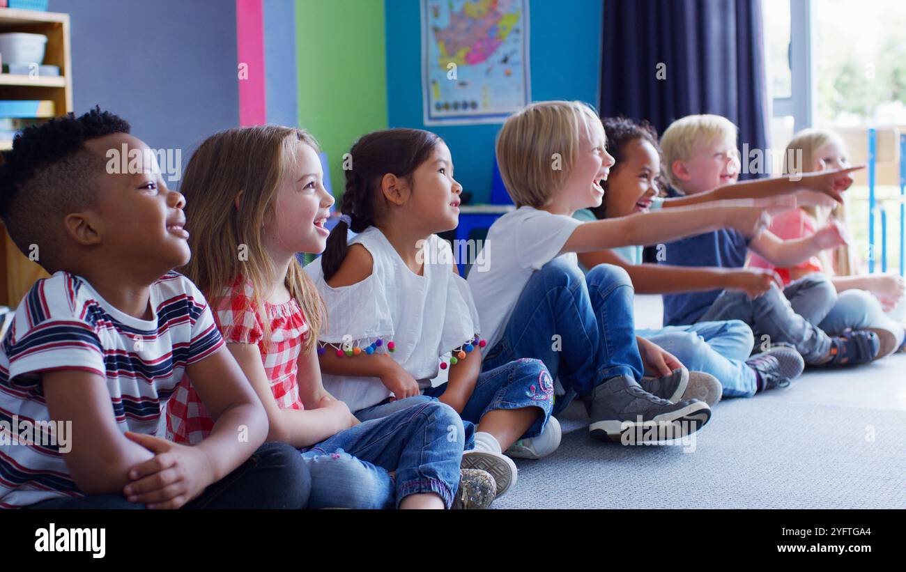 Group Of Smiling Elementary School Pupils Sitting On Floor In A Line ...