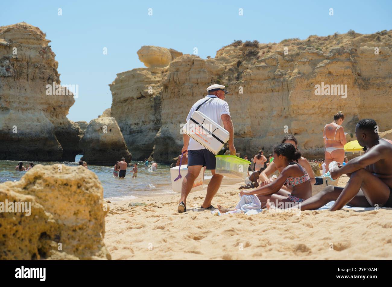 Vendor selling traditional bolas de berlim strolls along Praia de São ...