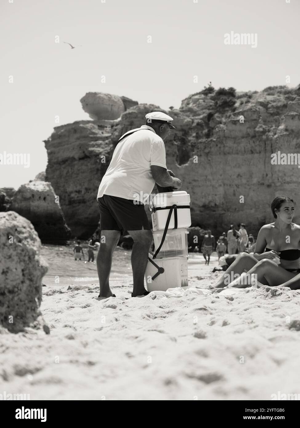Monochrome capture of a beach vendor selling traditional bolas de ...