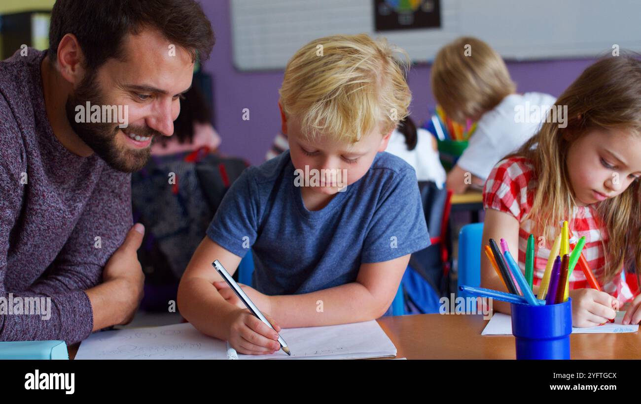 Male Elementary School Teacher Giving Male Pupil One To One Support In ...