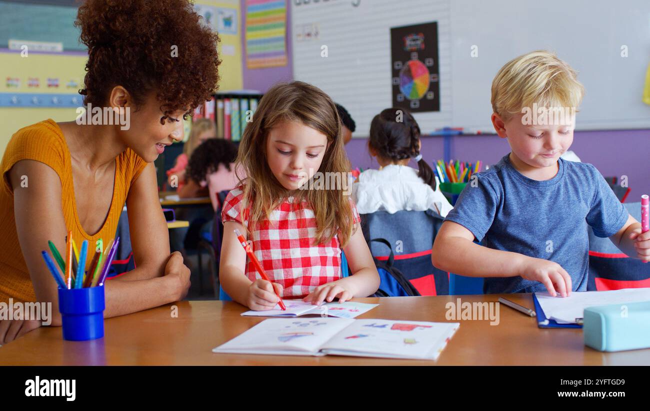 Female Elementary School Teacher Giving Female Pupil One To One Support ...