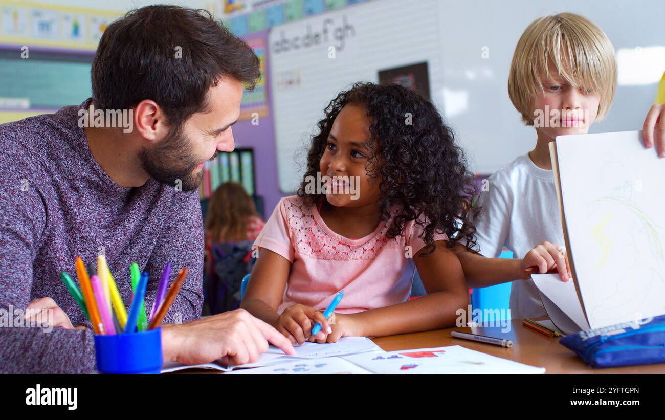 Male Elementary School Teacher Giving Female Pupil One To One Support ...