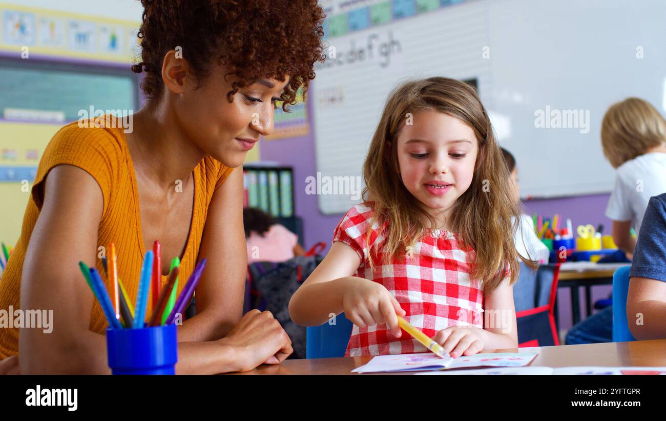 Female Elementary School Teacher Giving Female Pupil One To One Support ...