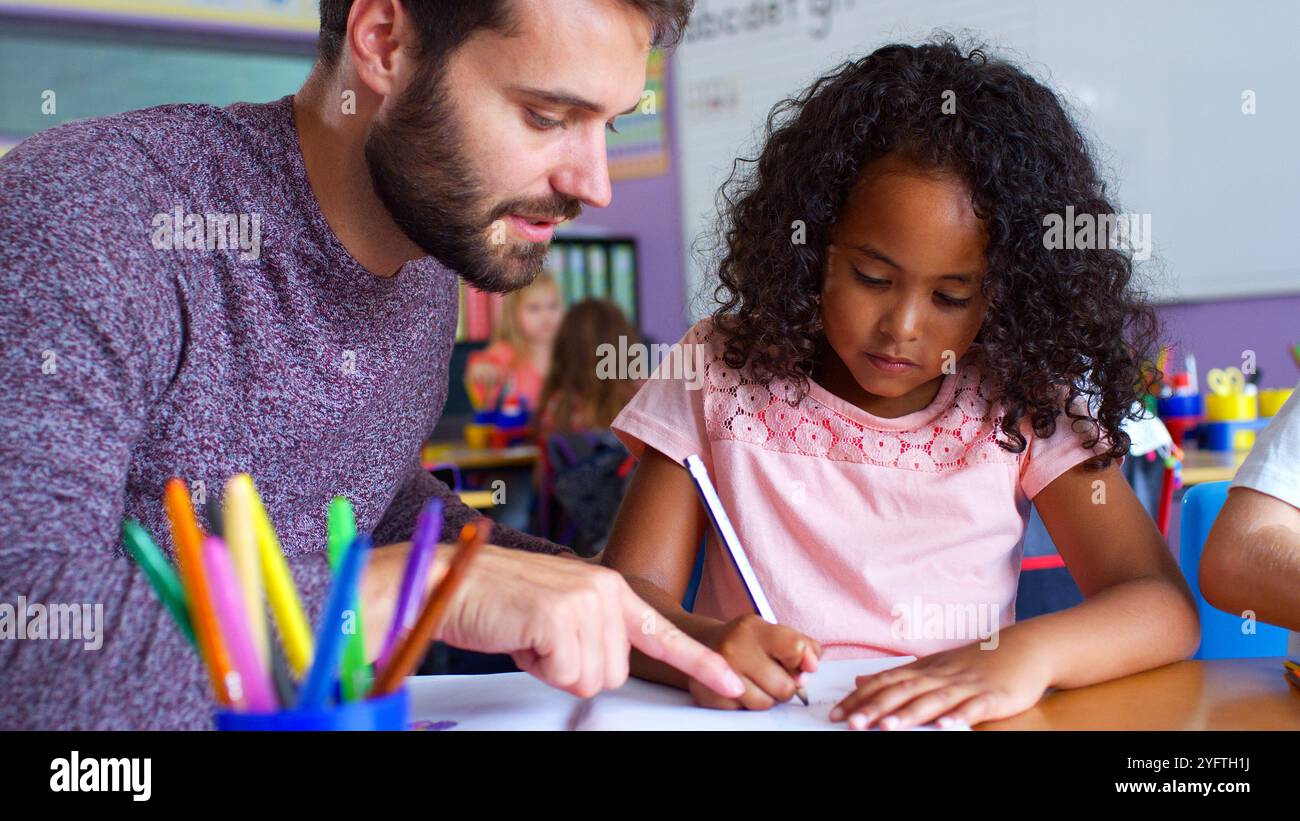 Male Elementary School Teacher Giving Female Pupil One To One Support ...