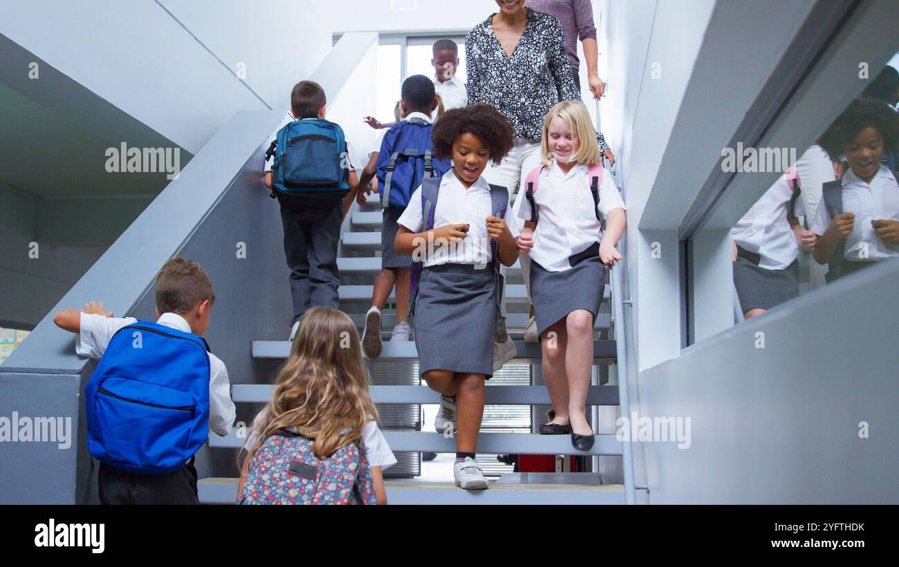 Teacher And Pupils Walking Down Stairs In Busy Elementary School ...