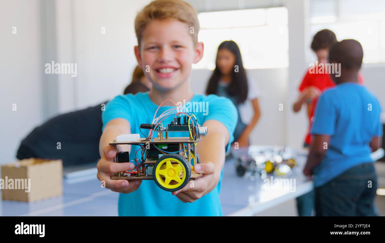 Portrait Of Smiling Male Student Holding Robot Vehicle Built In School ...