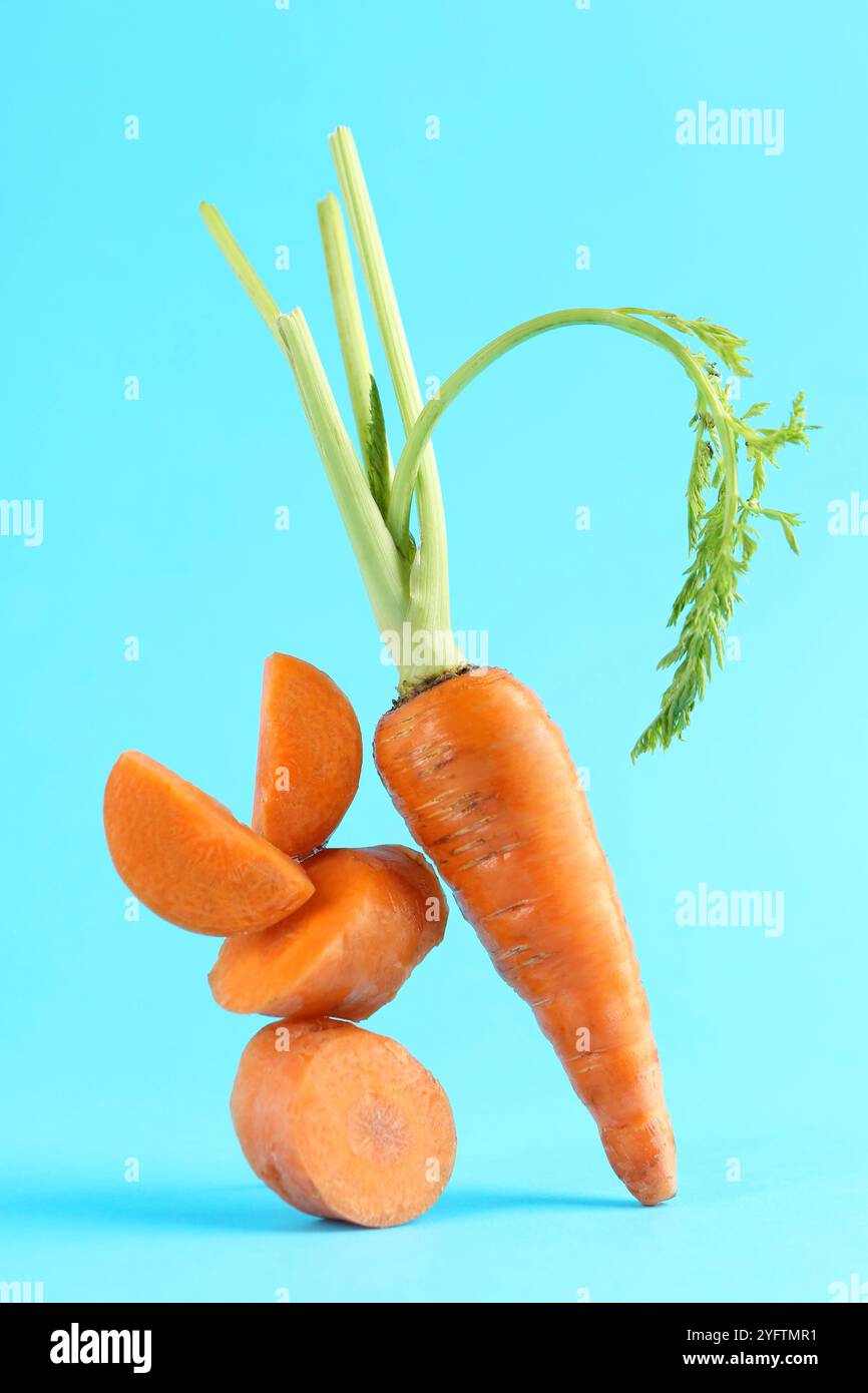 Whole and cut fresh carrots on light blue background Stock Photo - Alamy