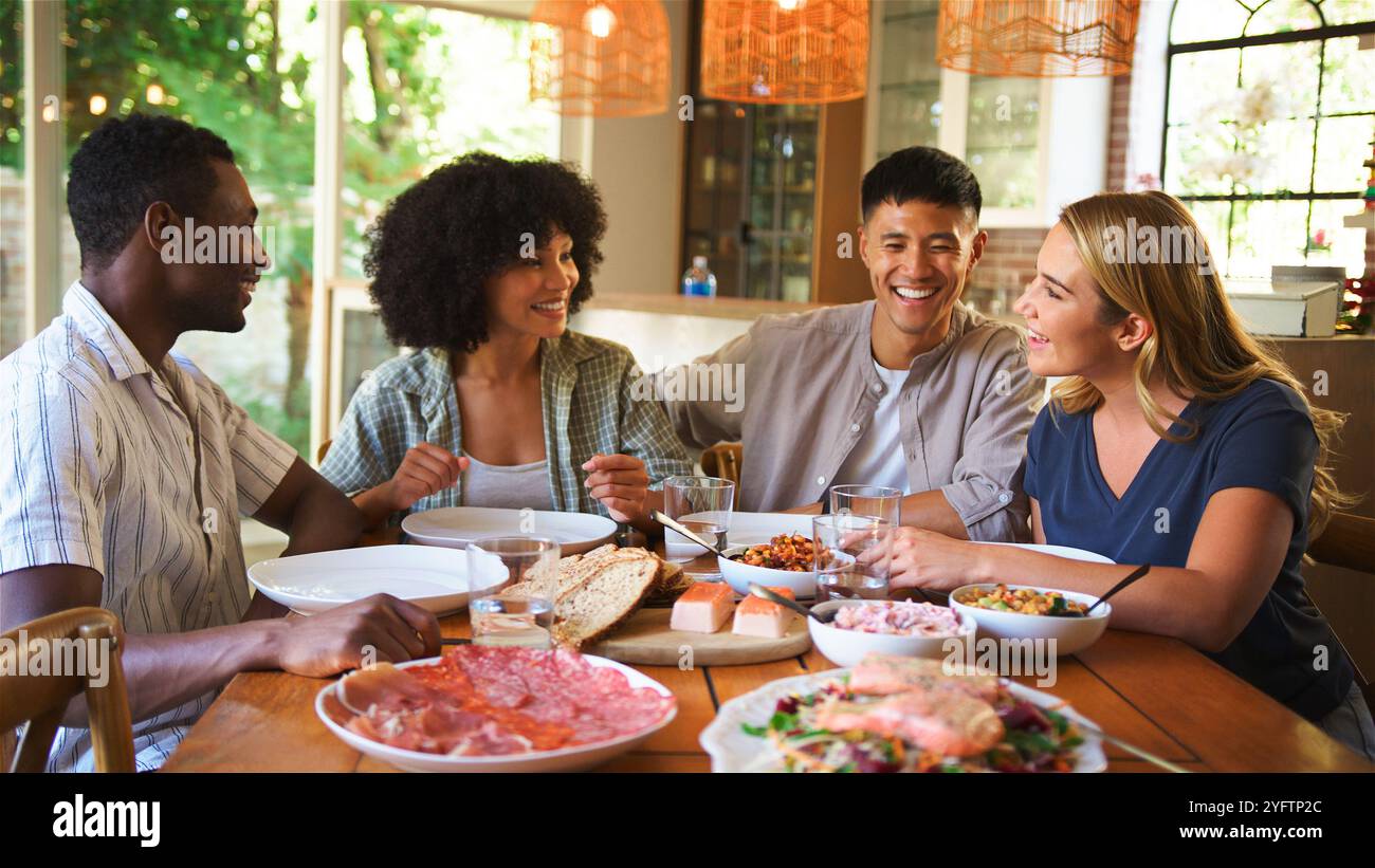 A group of four friends engages in cheerful conversation while sharing ...