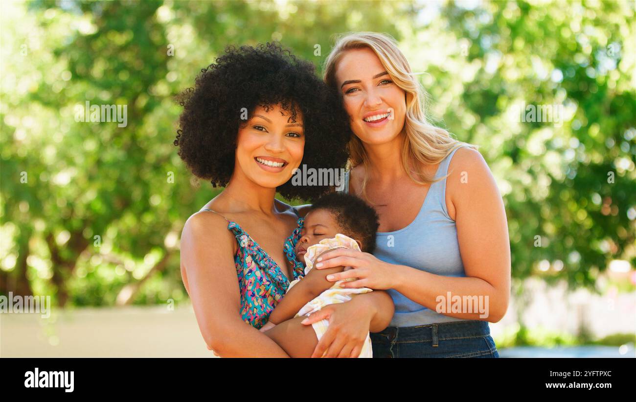 Two women happily embrace a baby in a bright, green environment Stock ...