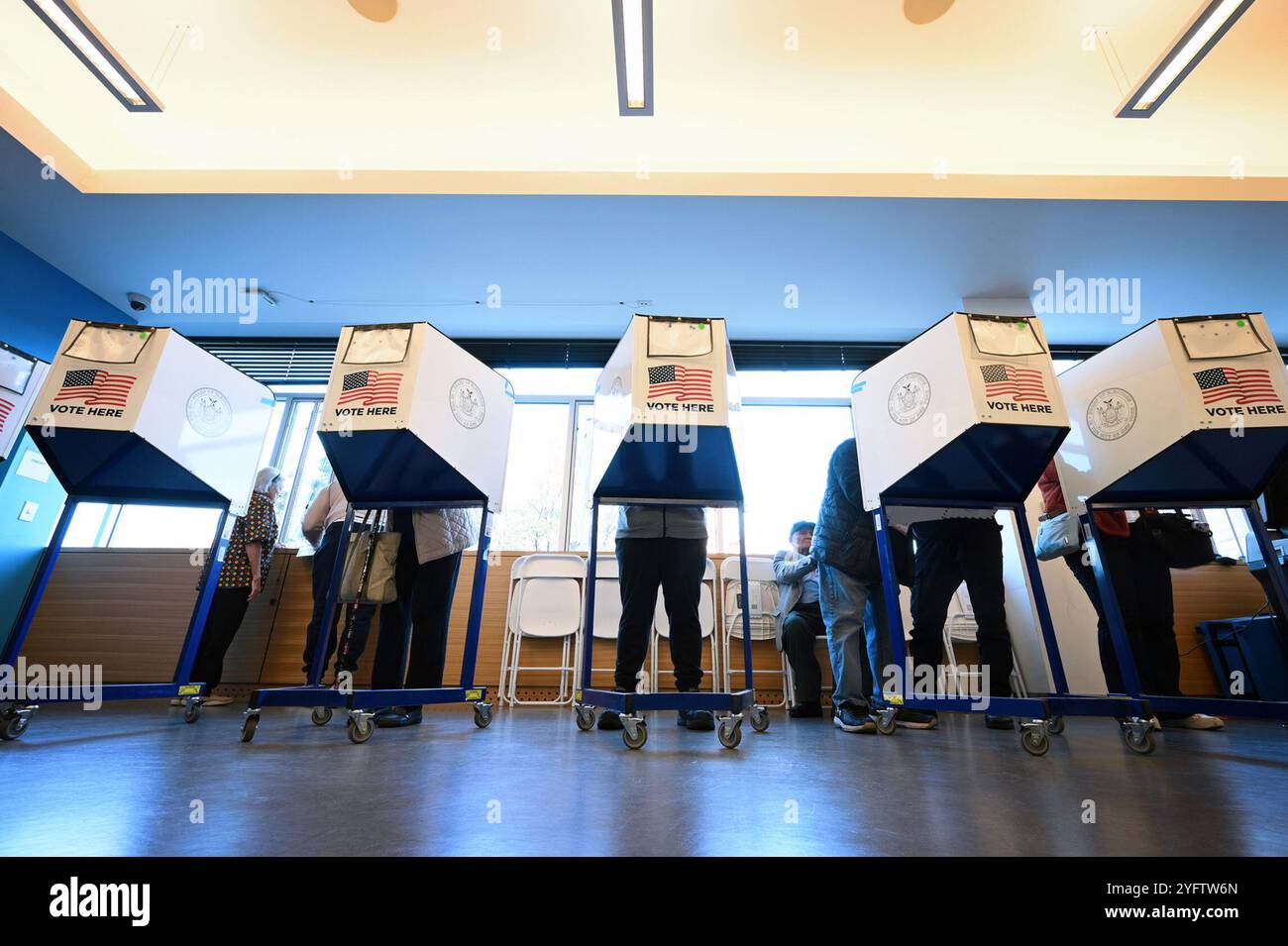 People stand behind privacy voting booths as they fill out their ...