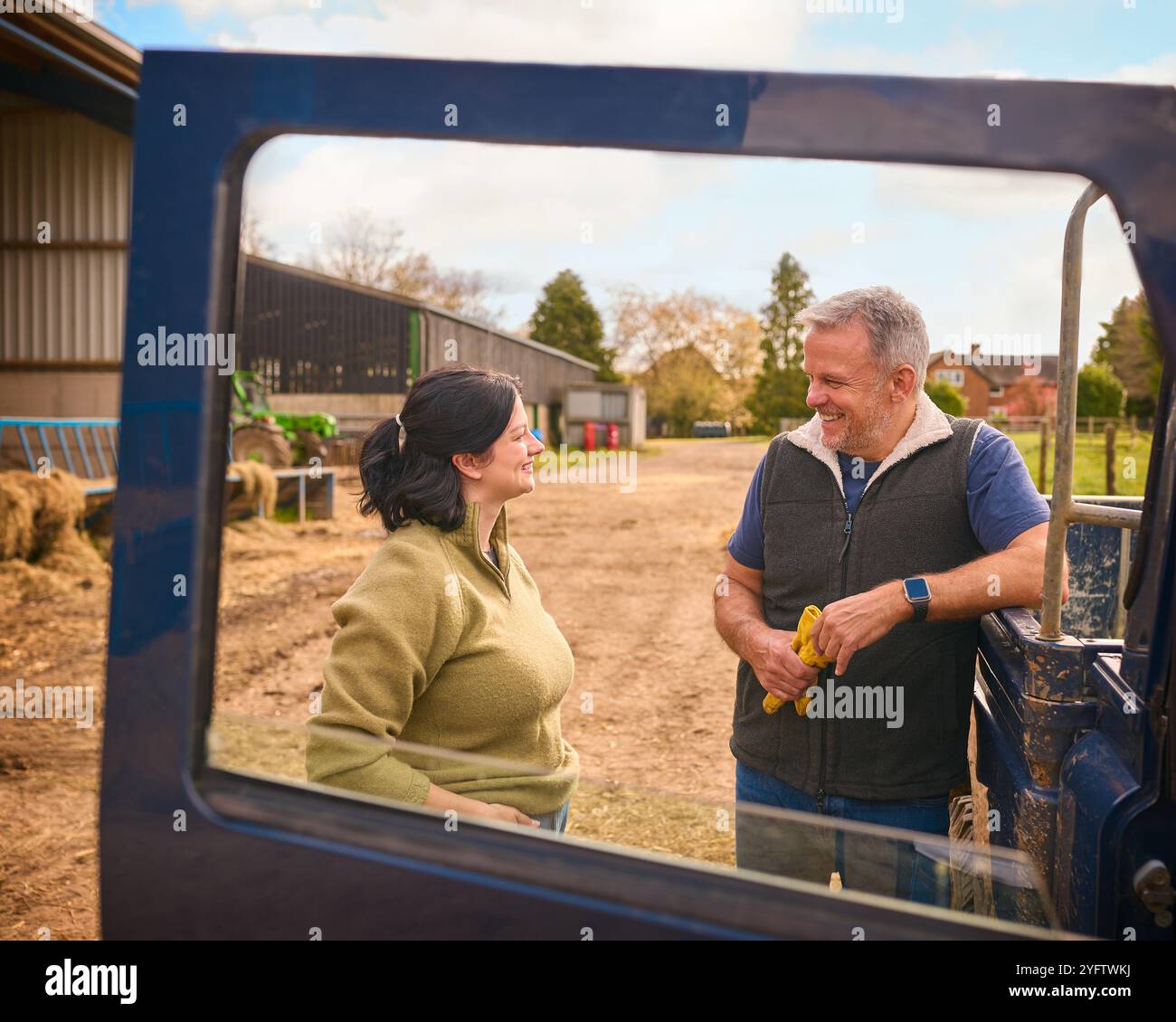 Male And Female Farm Workers Talking In Yard Viewed Through Window Of ...