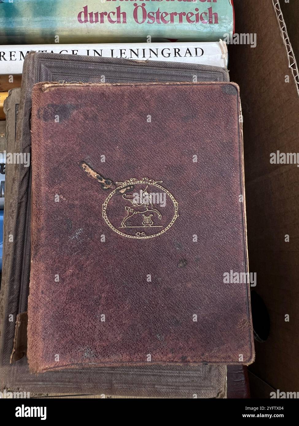 An old, worn book with a textured cover and an ornate emblem ...