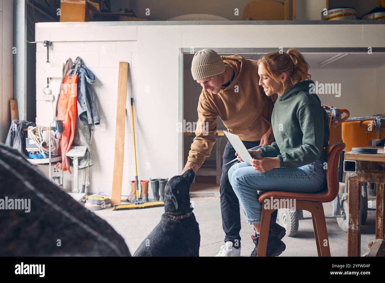 Male And Female Workers With Dog Meet In Concrete Workshop With Laptop ...