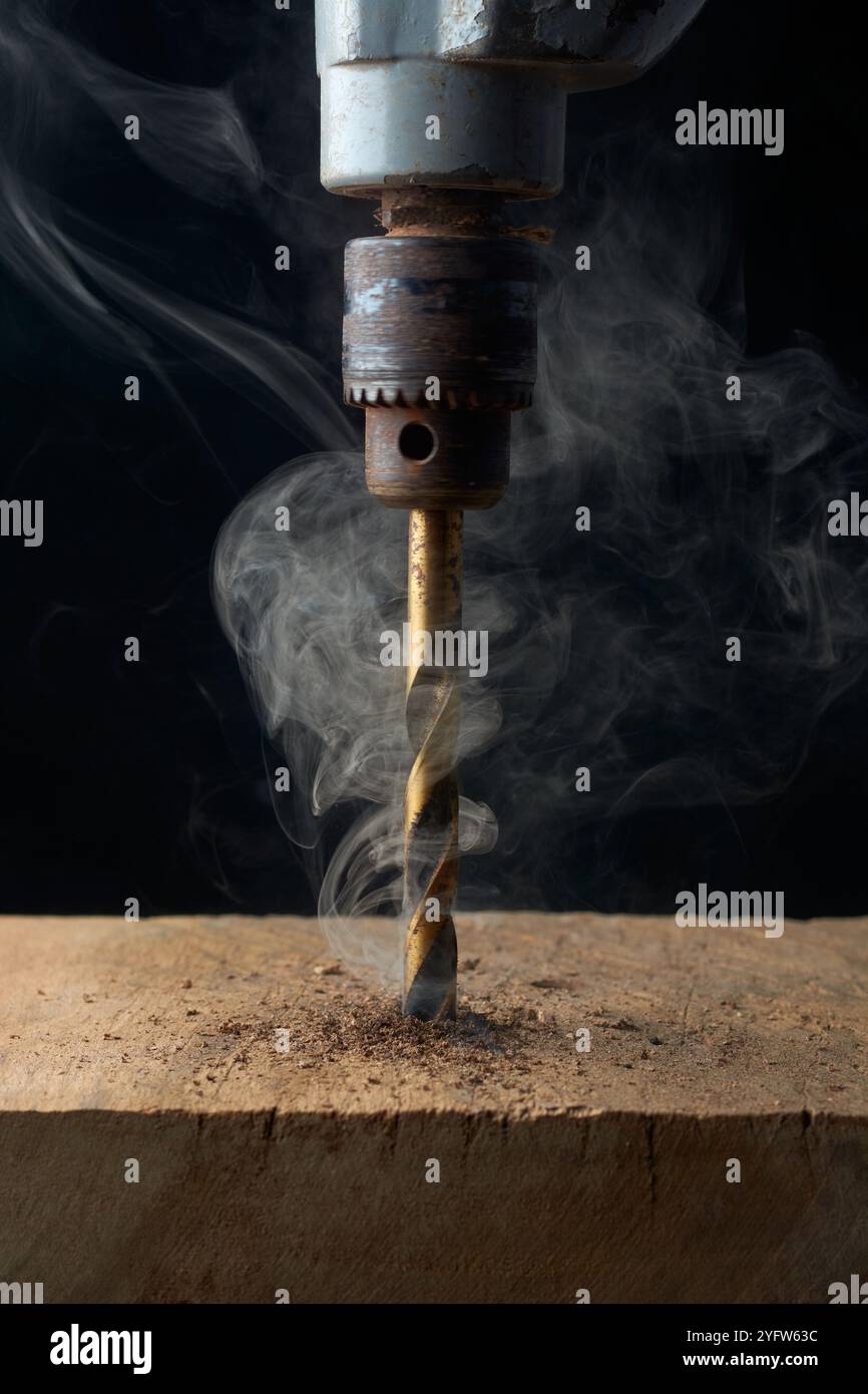 closeup of drilling hole with dull drill bit in hardwood with smoke and ...