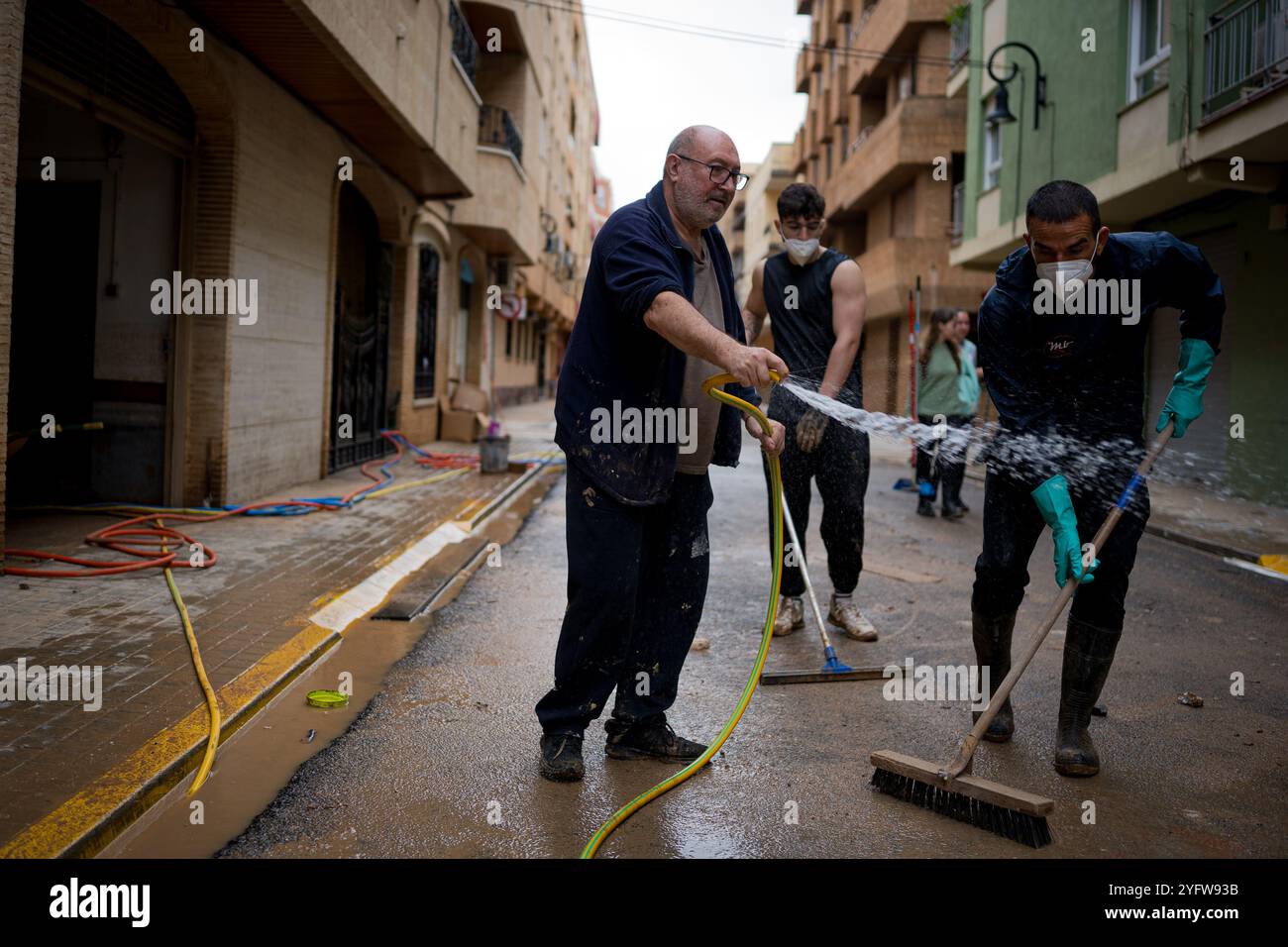 Locals and volunteers are seen manually cleaning up the streets filled ...
