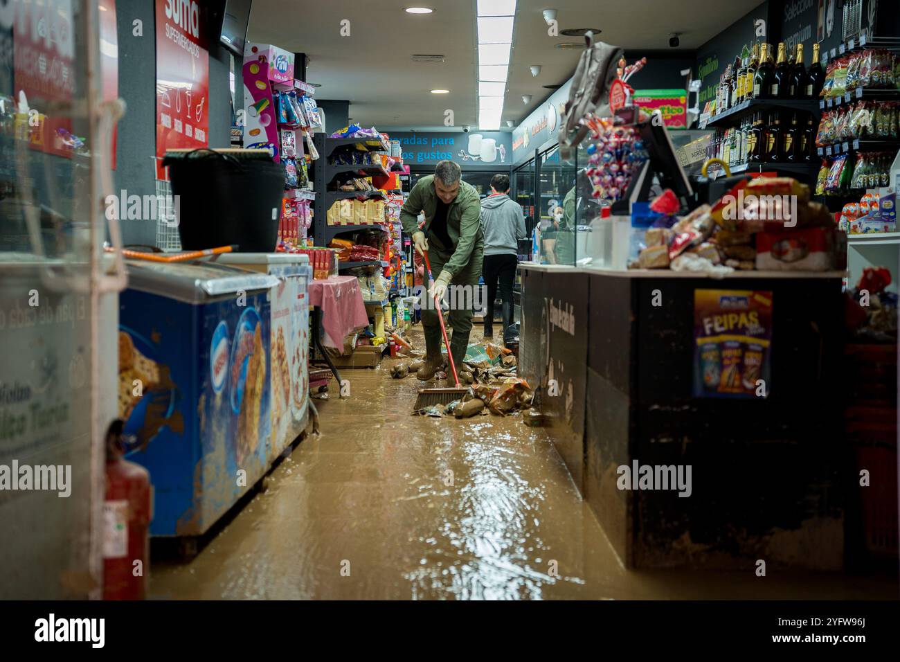 A man is seen cleaning his store after the floods. More than 200 people ...
