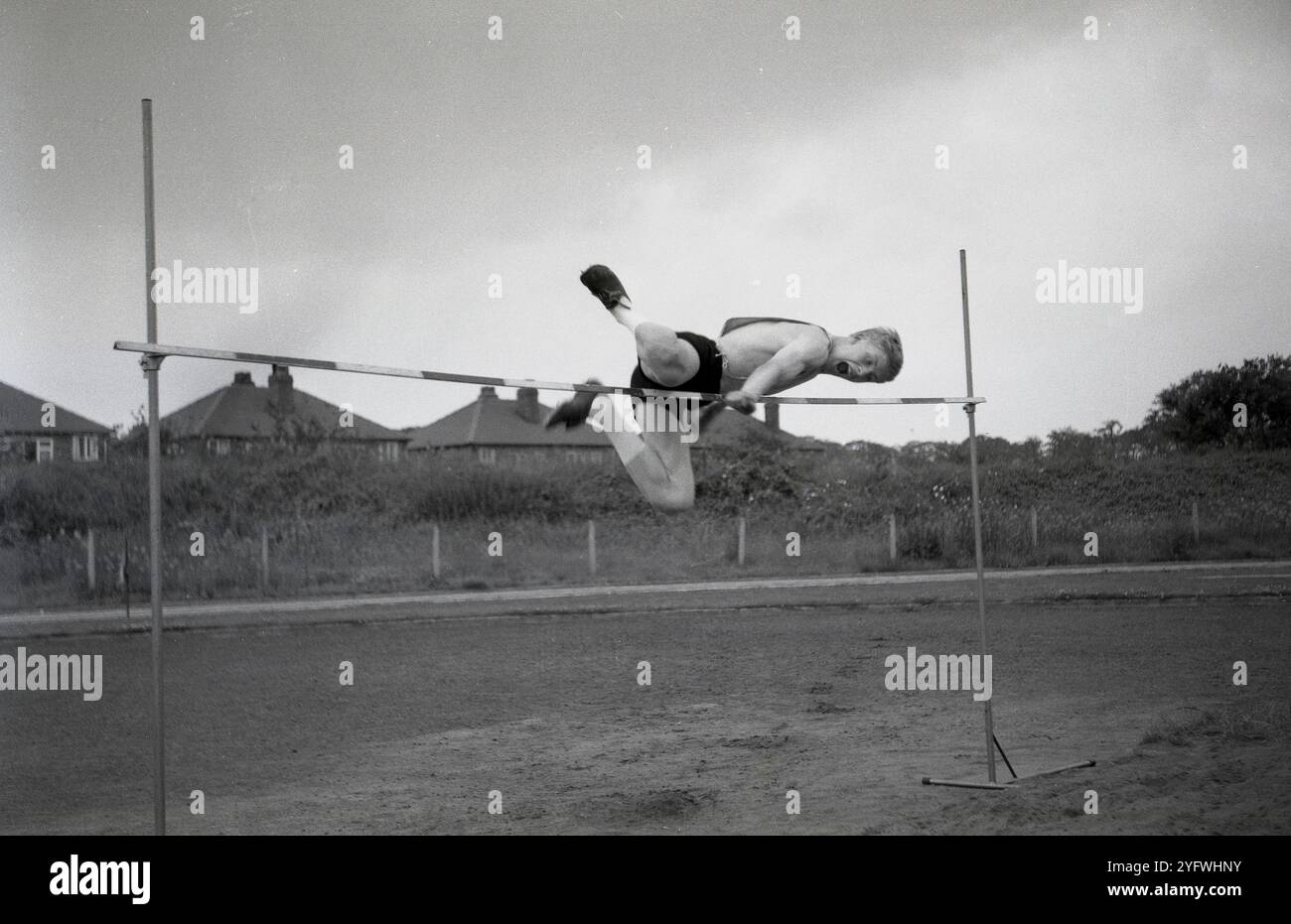 1960s, historical, in a school sports high jump, an animated young man ...