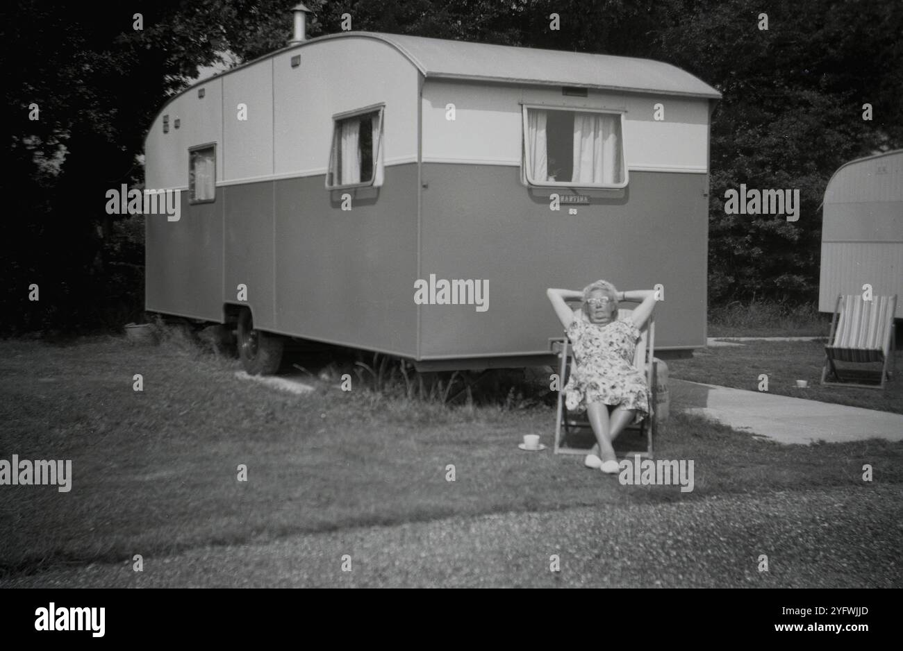 1950s, historical, a mature lady relaxing in a deckchair in front of ...
