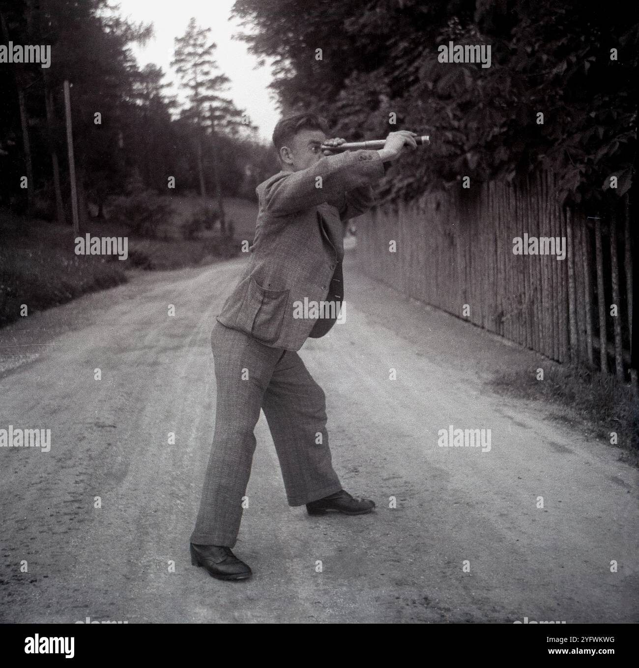 1950s, historical, a man in a check patterned suit standing, feet wide ...